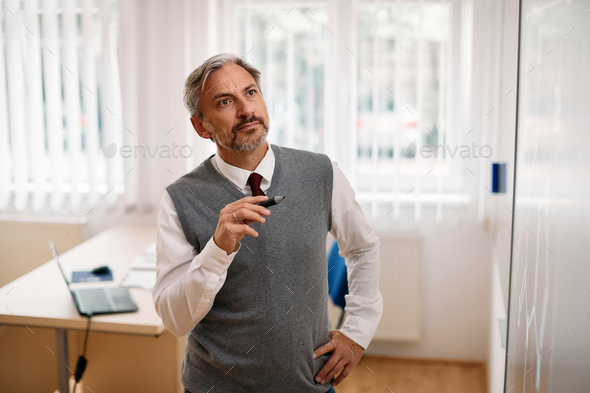 Mature professor thinking while solving formula on whiteboard in the classroom. Stock Photo by ...